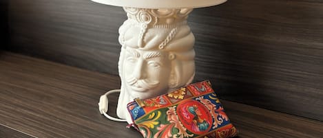 Um abajur branco com base decorativa sobre um banco de madeira.
