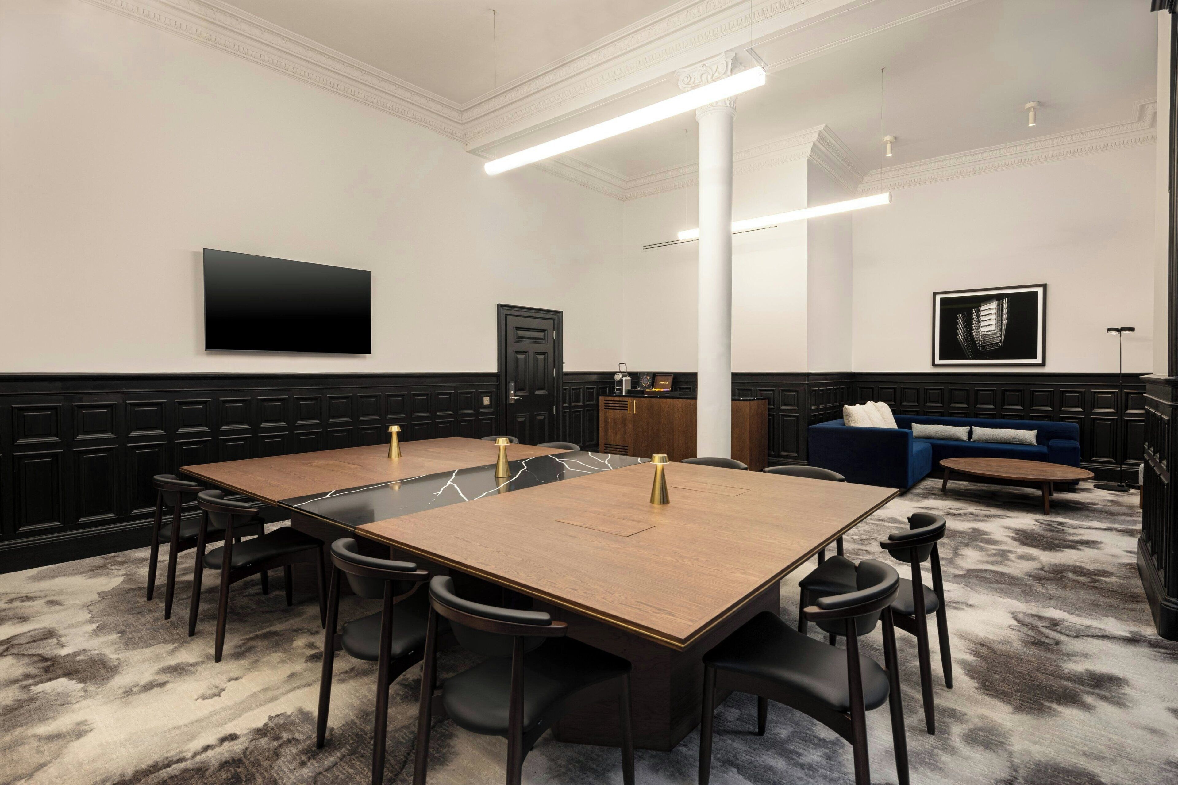 Uma sala de conferência com uma mesa grande, cadeiras, um sofá e uma televisão.