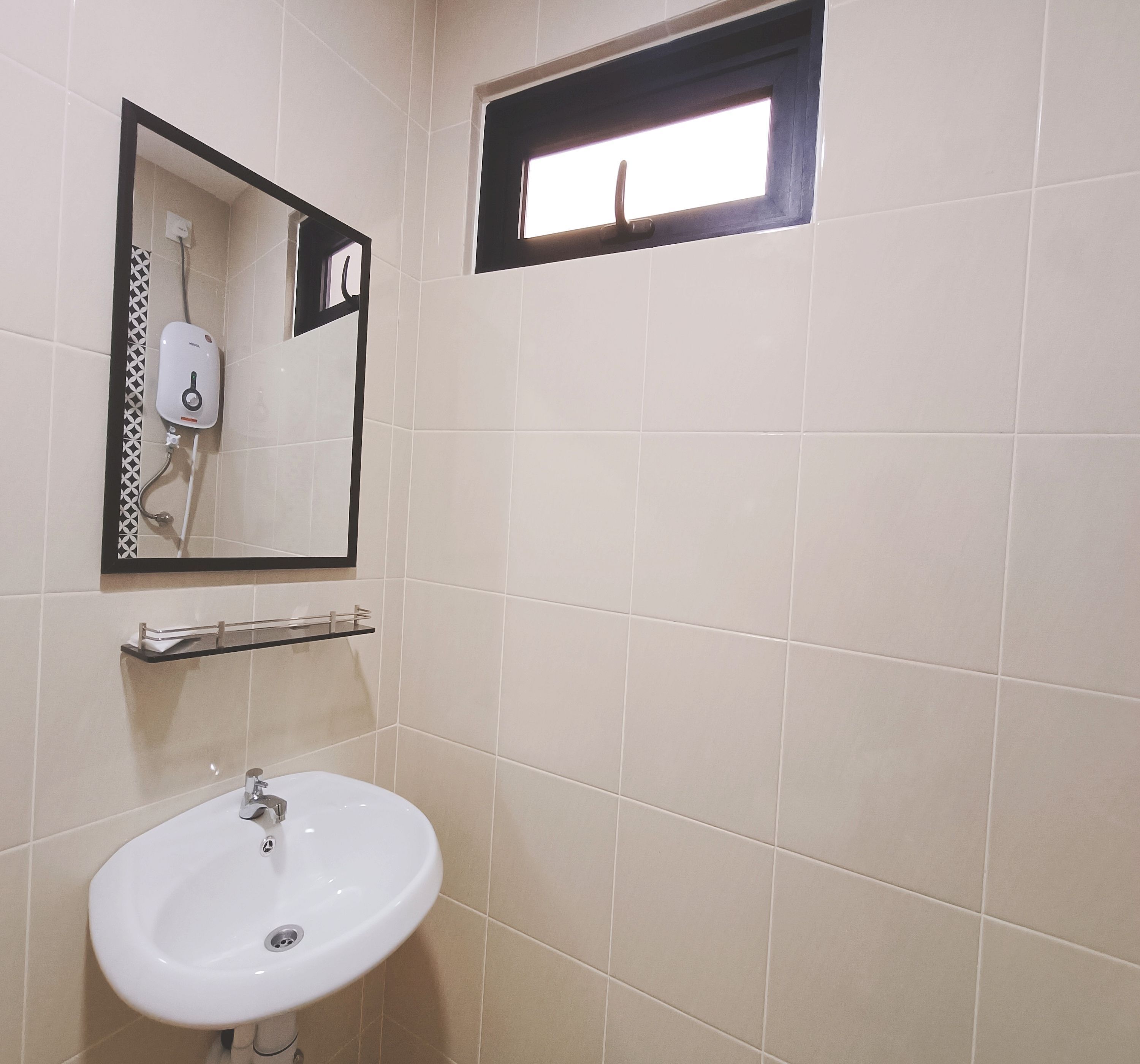 Uma casa de banho com uma pia branca, um espelho, um porta-toalhas e uma janela.