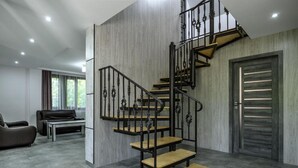 Um interior moderno com escada em espiral, paredes cinzentas e uma porta fechada.