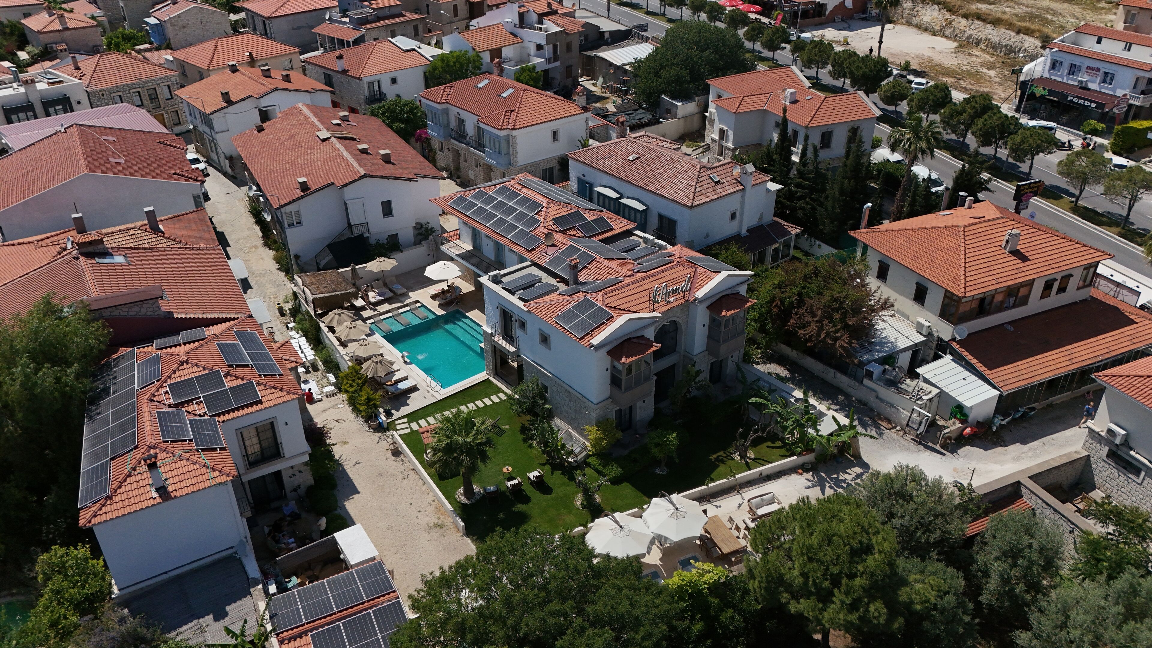 Uma área residencial com várias casas, uma piscina e painéis solares nos telhados.