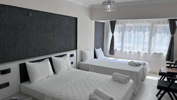 Quarto de hotel com duas camas, uma escrivaninha e uma cadeira.