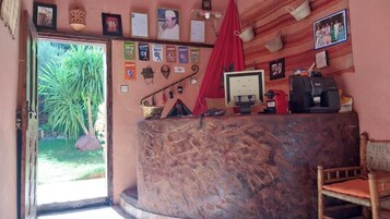 Uma área de recepção com balcão de mármore, um computador e diversos objetos emoldurados na parede.