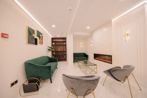 Uma sala de estar moderna com um sofá verde, uma poltrona cinza, uma mesa de centro e uma estante.
