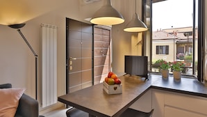 Uma cozinha moderna com uma mesa de madeira, uma fruteira, luminárias pendentes e vista para o bairro.