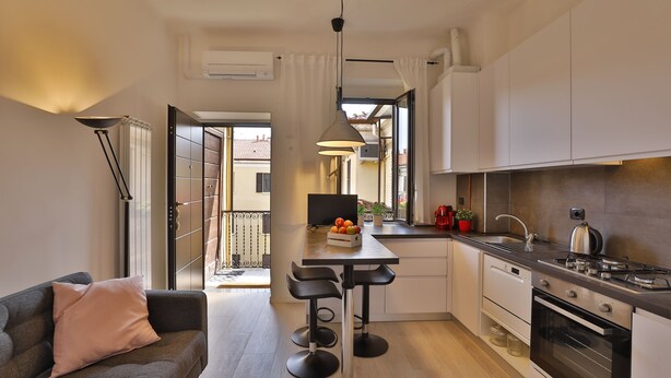 Cozinha moderna com área de jantar, sofá e vista para o exterior.