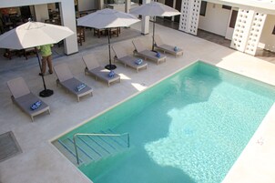 Uma área de piscina com espreguiçadeiras e guarda-sóis.