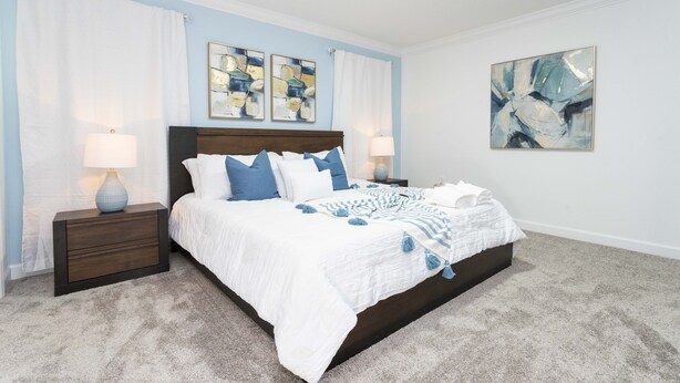 Quarto com cama, duas mesas de cabeceira, cabeceira e obra de arte na parede.