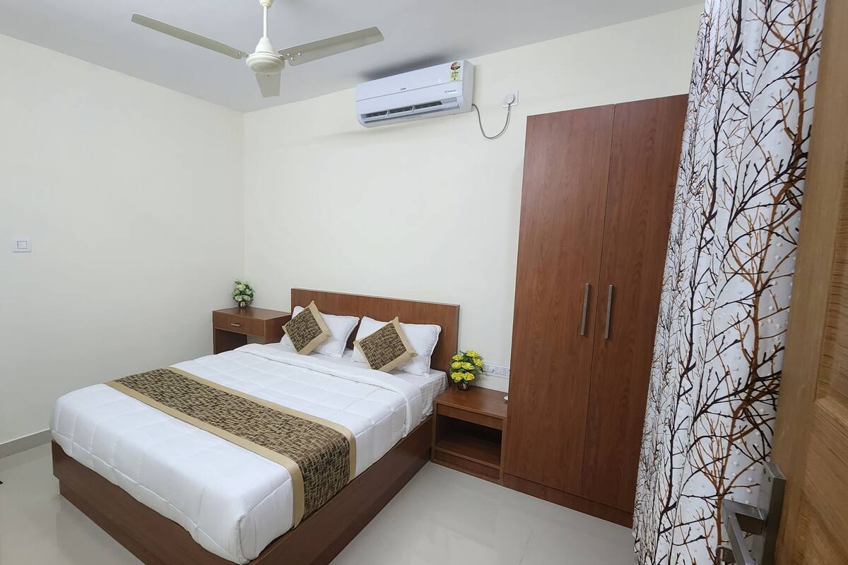 Quarto com cama, guarda-roupa de madeira e ventilador de teto.