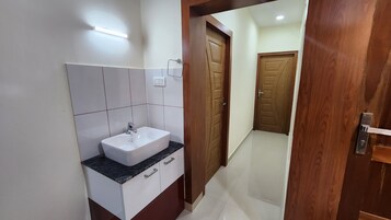 Casa de banho com lavatório branco, espelho e porta de madeira.