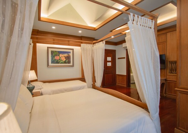 Quarto com duas camas, cabeceiras de madeira, um quadro na parede e uma televisão.