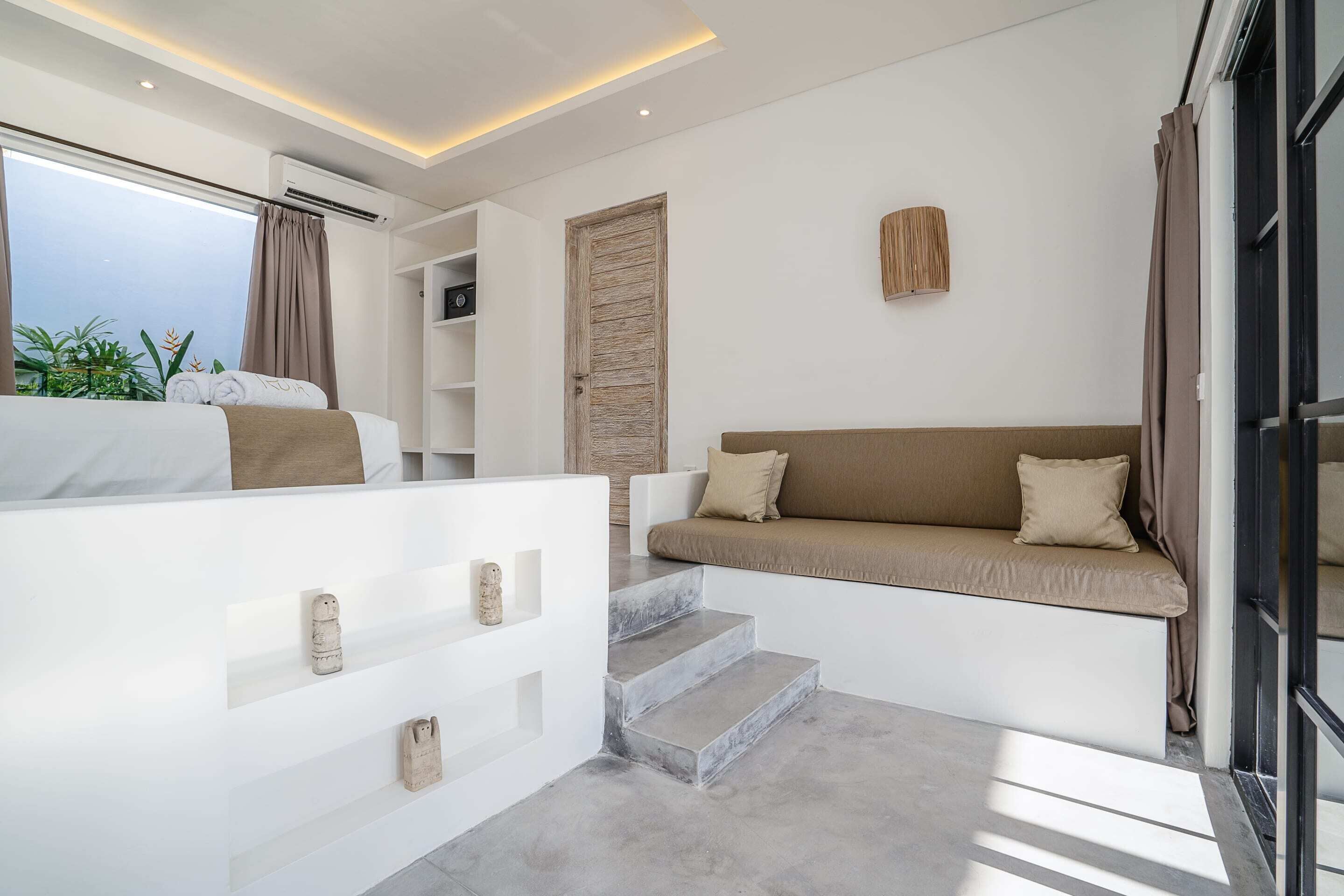Quarto moderno com cama, sofá, escada e vista para o exterior.