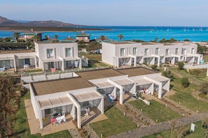 Um resort moderno com vários edifícios brancos, áreas de estar ao ar livre e vista para o mar.