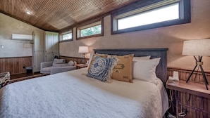 Quarto com uma cama grande, teto de madeira e janela.
