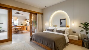 Quarto moderno com uma cama grande, mesas de cabeceira e uma luminária de parede curva.