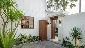 Um edifício moderno com fachada branca, porta de madeira e varanda.