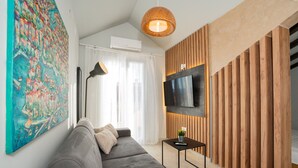 Uma sala de estar moderna com um sofá cinza, uma TV de tela plana fixada em uma parede de painéis de madeira e um quadro abstrato grande à esquerda.