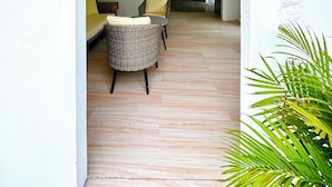 Um corredor com um arco branco que leva a uma área de estar com móveis de vime e um ventilador de teto.