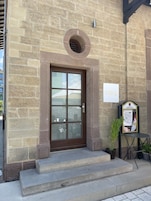 Um edifício de pedra com porta marrom, um letreiro com a palavra 