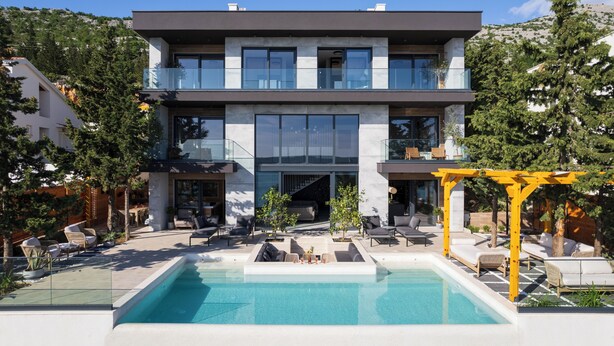 Uma casa moderna de dois andares com piscina, área de estar externa e pérgola.