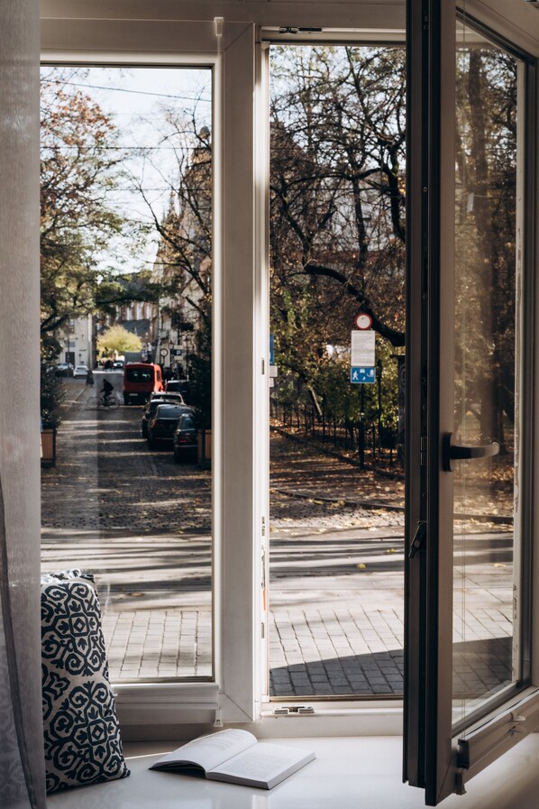 Quarto com uma janela grande que oferece vista para uma rua com carros e uma bicicleta.