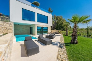 Uma casa moderna de dois andares com piscina, área de estar externa e um jardim bem cuidado.