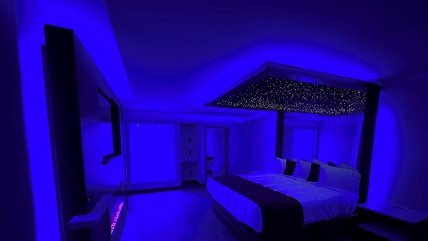 Quarto moderno com cama grande, luminária no teto e mesa de cabeceira.