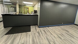 Uma área de recepção com balcão, espelho, porta e parede com detalhes azuis.