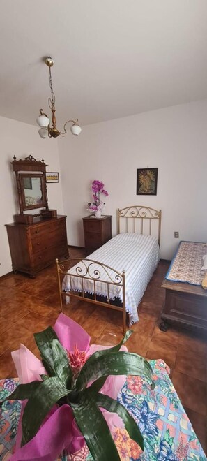 Quarto com cama, penteadeira, cômoda e lustre.