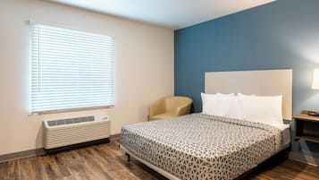 Quarto com cama, cadeira, mesa de cabeceira, aquecedor e janela com persianas.