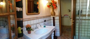 Casa de banho com lavatório, espelho e um vaso com flores.