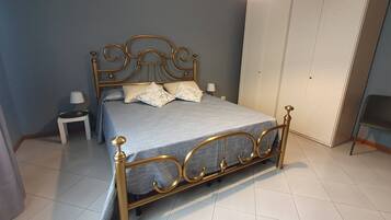 Quarto com cama, mesa de cabeceira e guarda-roupa.