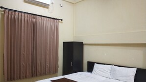 Quarto de hotel com cama, guarda-roupa e cortina.