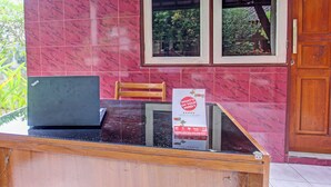Uma mesa de recepção com um laptop, uma placa de identificação e uma janela com vista para o verde.