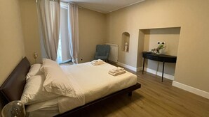 Quarto com cama, cadeira, escrivaninha e radiador.