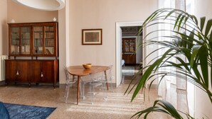 Uma área de refeições com mesa e cadeiras de madeira, um armário com portas de vidro e uma planta grande.