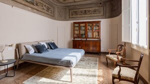 Quarto com cama, armário de madeira, cadeira e janela.