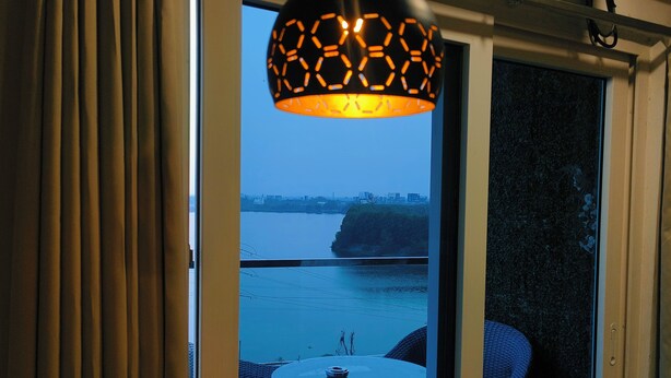 Quarto com vista para a água e um horizonte urbano ao longe.