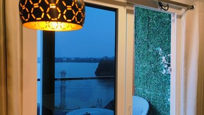 Varanda com mesa e cadeiras, vista para a água e um muro decorativo.