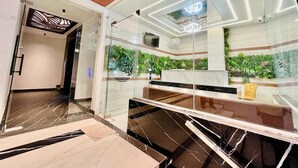 Um lobby moderno com divisória de vidro, balcão de recepção e parede verde com plantas.