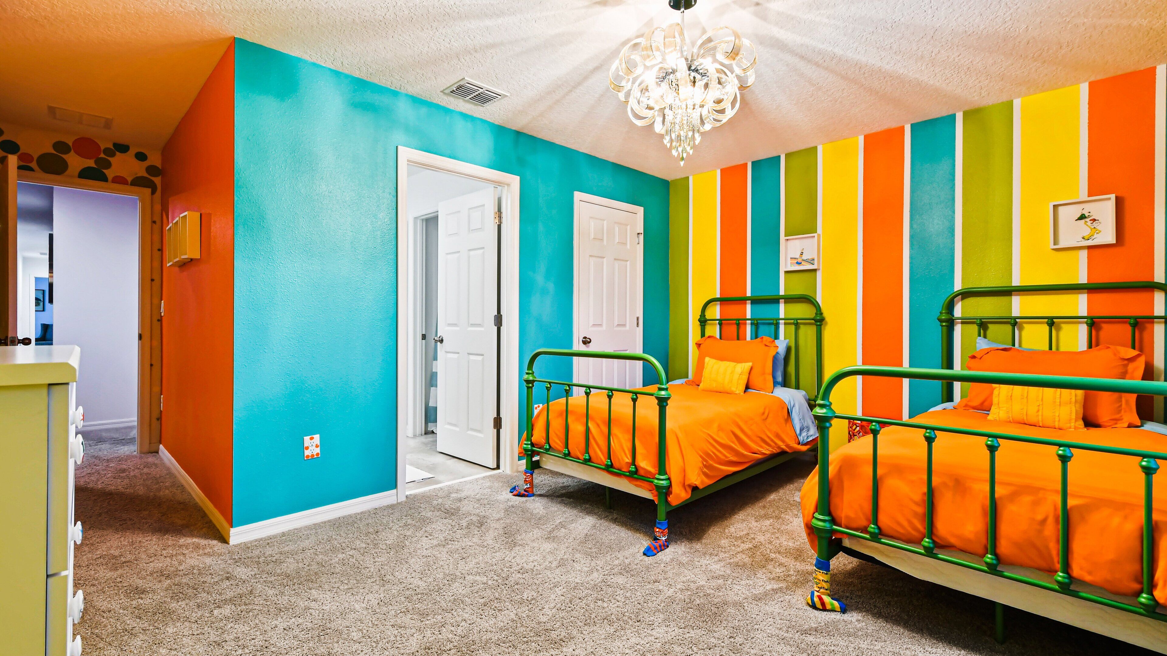 Um quarto vibrante, com duas camas de metal verde, um candelabro e uma porta.