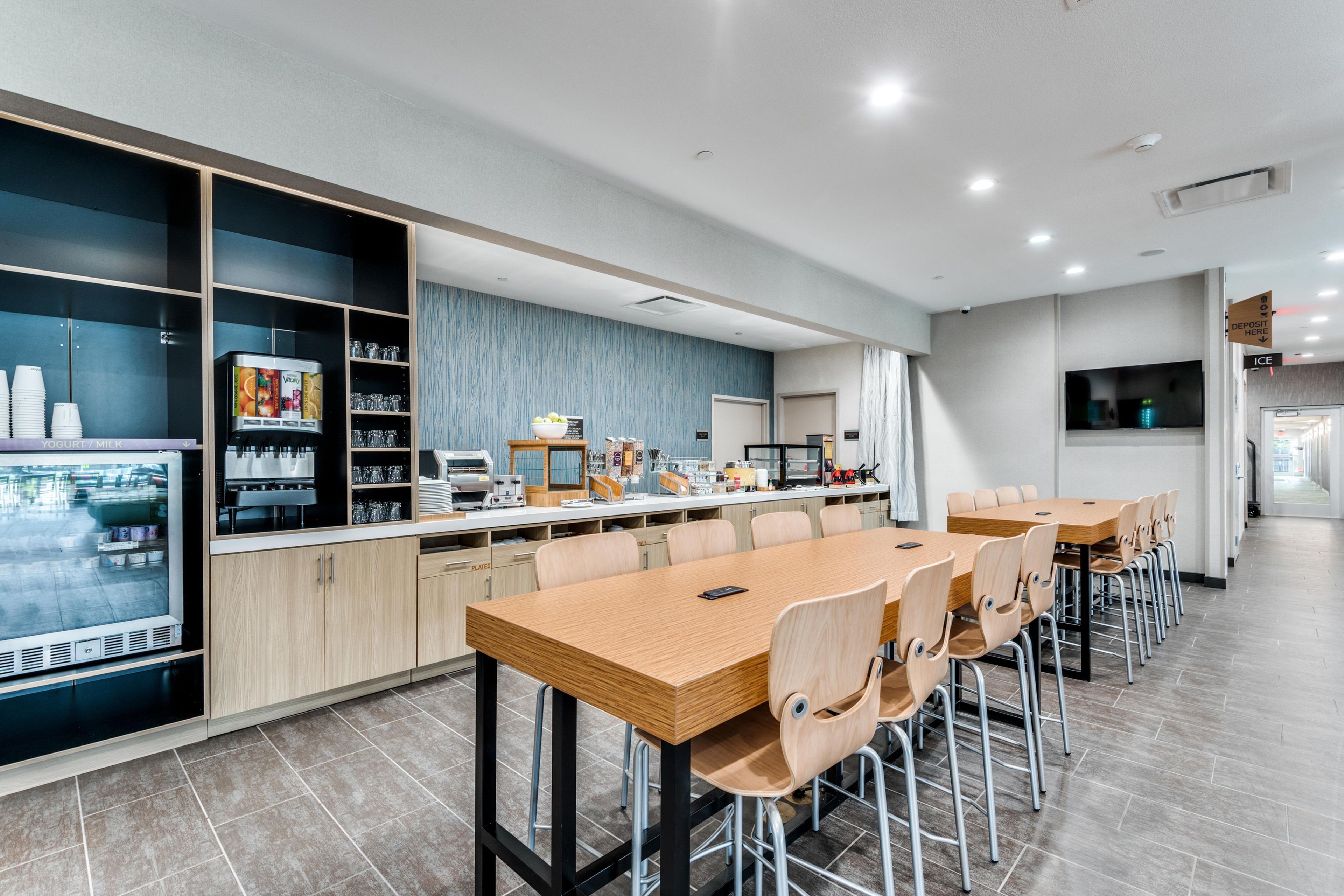 Um café moderno com um balcão comprido, área de estar e um refrigerador.