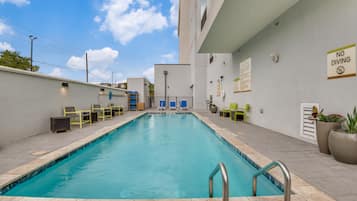 Piscina interna com placa indicando 'proibido mergulhar', rodeada por espreguiçadeiras e céu claro.