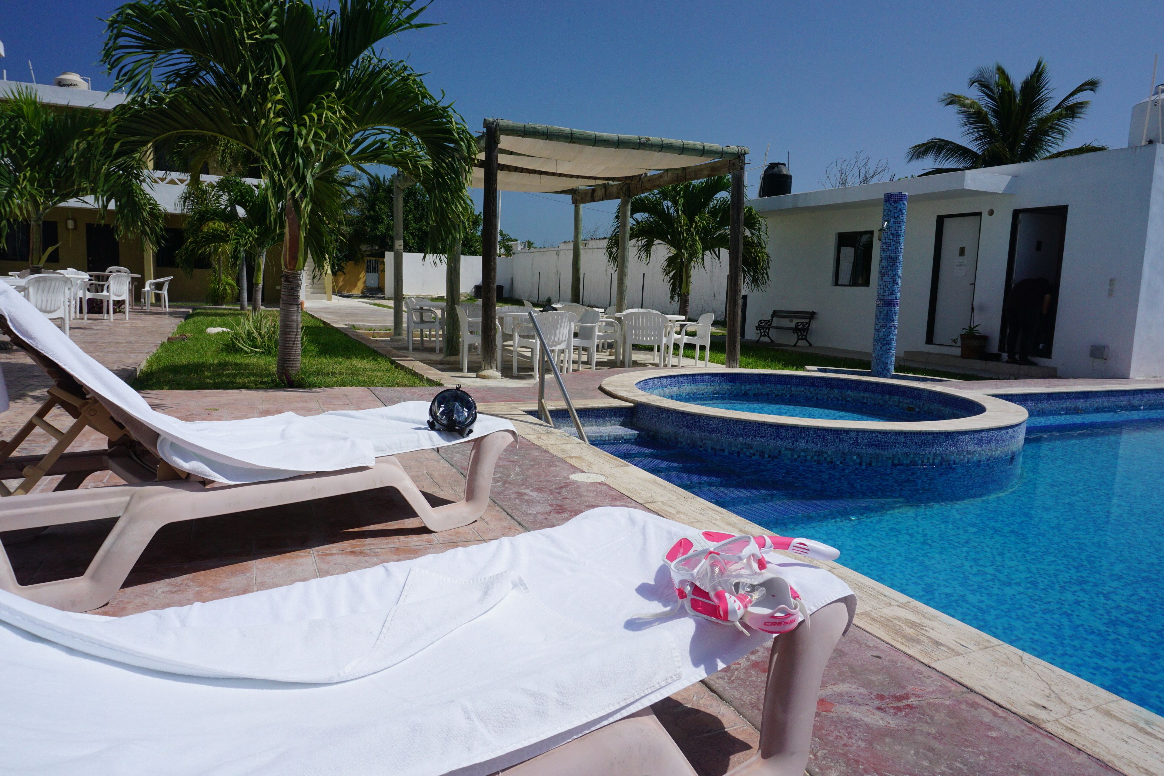Uma área de piscina com espreguiçadeiras, um espaço coberto para sentar e uma piscina pequena.