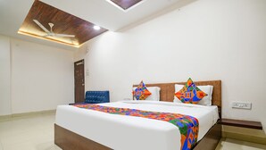 Quarto com estrutura de cama de madeira, ventilador de teto e colcha estampada.