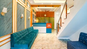 Uma área de recepção com um sofá azul-turquesa, um balcão de atendimento e uma escada.