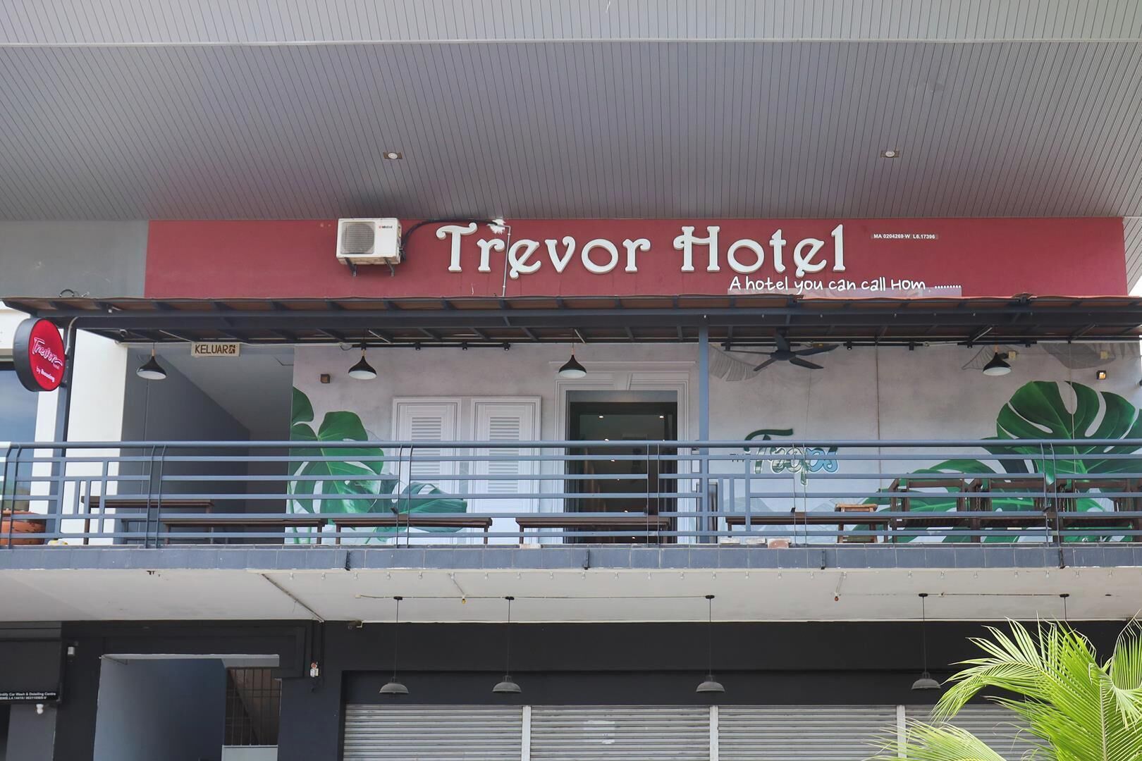 Exterior do Trevor Hotel, com toldo vermelho, placa de identificação e varanda com grades.