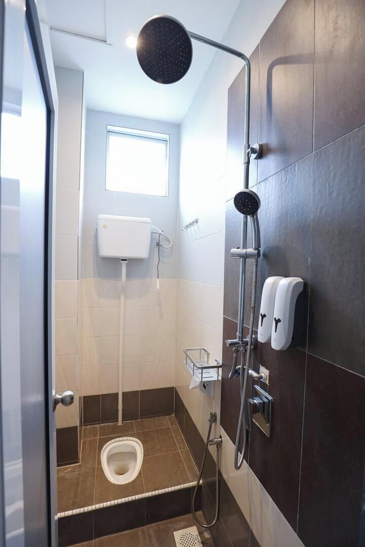 Uma casa de banho moderna com chuveiro, sanita e janela.