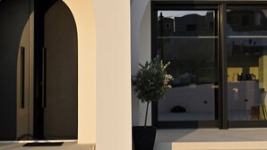 Um edifício moderno com uma grande entrada em arco, porta de vidro e uma pequena planta em vaso.
