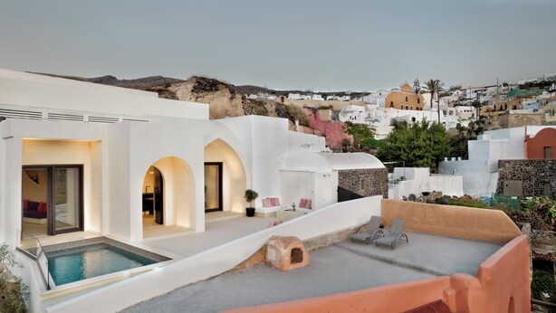 Um edifício moderno e branco com piscina, portas em arco e área de estar no terraço.